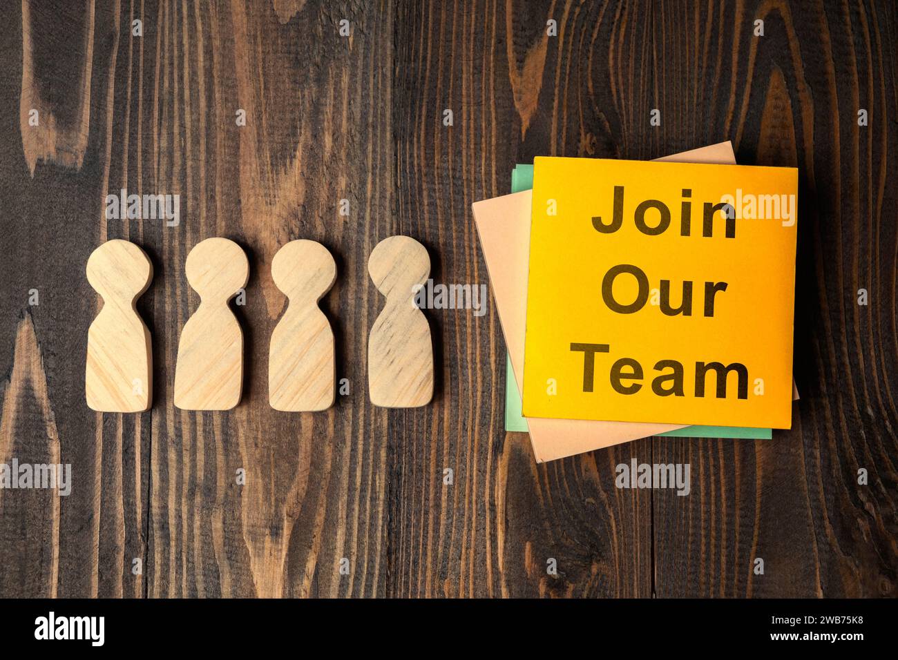 Wooden figures and a stack of note paper with Join Our Team text on a ...