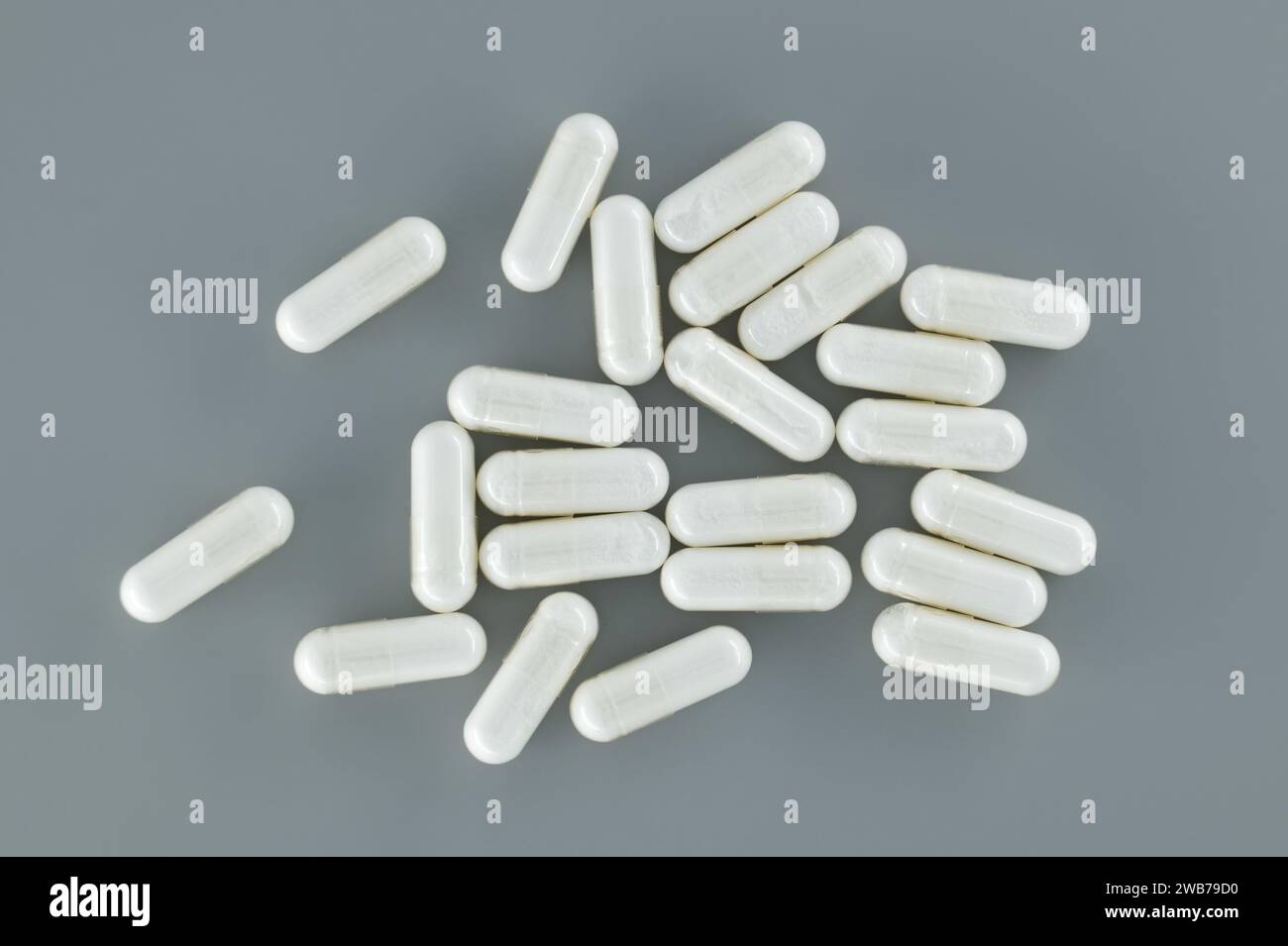 Large number of white pills scattered on a gray surface. Minimal ...