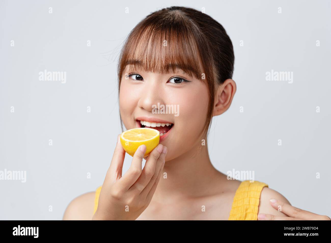 Beauty portrait of asian young woman smiling and eating lemon isolated ...
