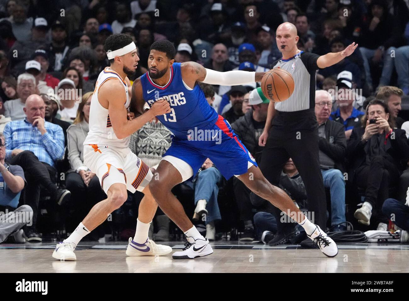 Los Angeles Clippers forward Paul George, center, pushes against Phoenix Suns guard Devin Booker ...