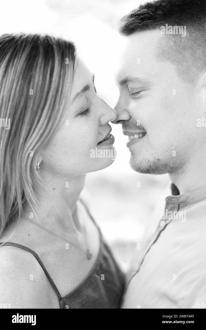 Smiling man and woman almost kiss with their eyes closed. Black and ...