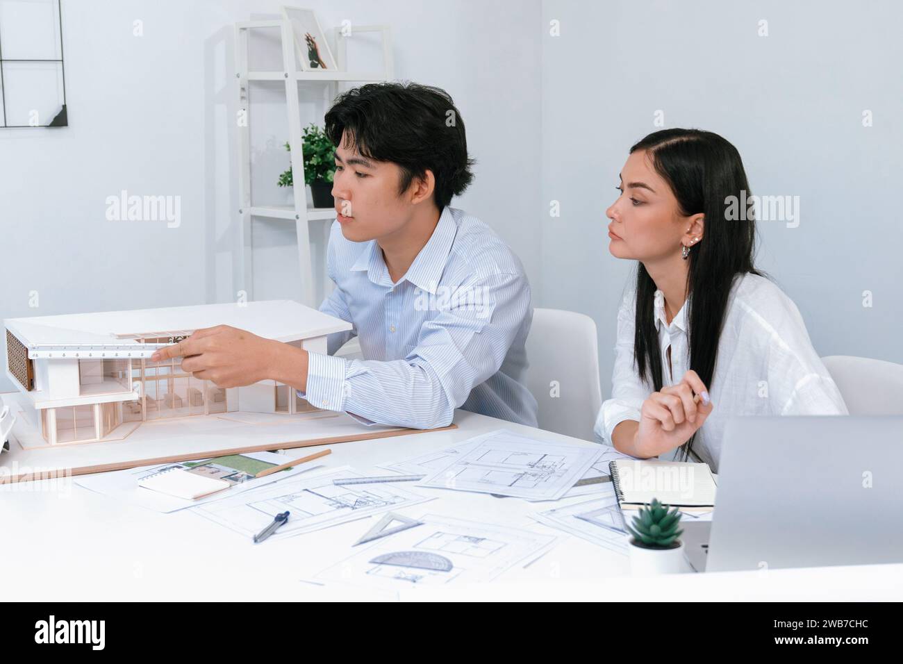 Professional male asian architect using ruler to measure house model ...