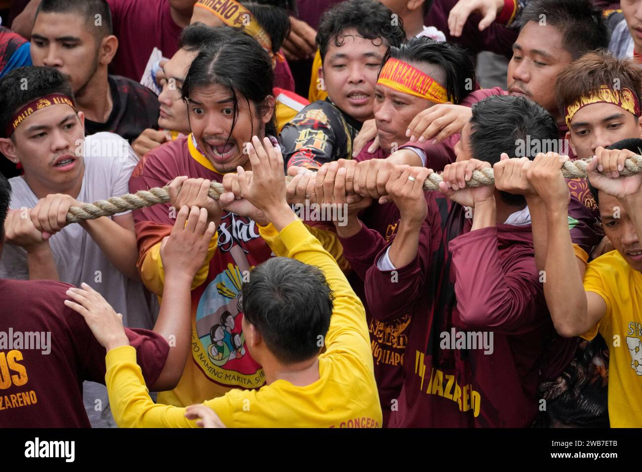 Devotees grab the rope as they pull the glass-covered cart carrying ...
