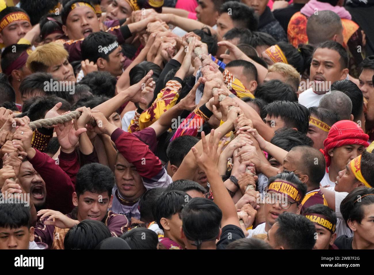 Devotees grab the rope as they pull the glass-covered cart carrying ...