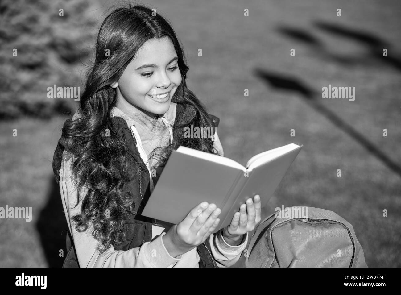 photo of positive school teen girl read in park. school teen girl read ...