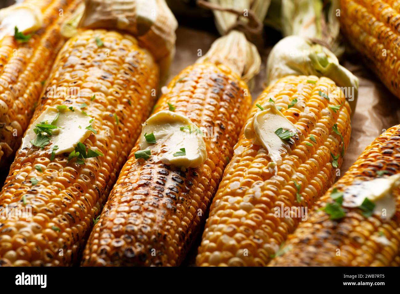 Grilled sweet corn cobs with butter seasoned with cilantro closeup low ...