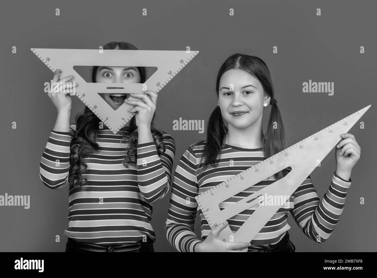 smiling school girls hold math tool of triangle Stock Photo - Alamy