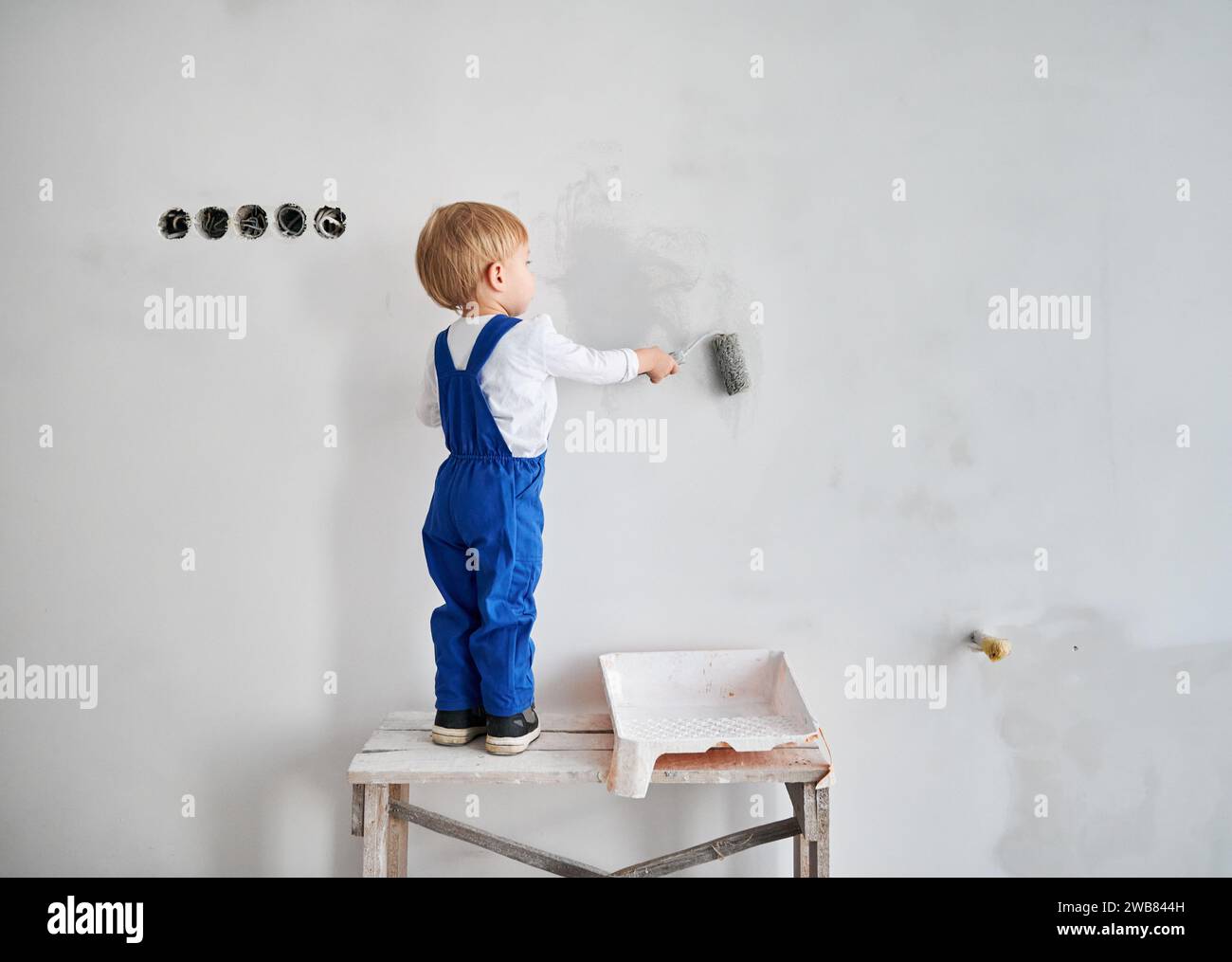 Back view of child construction worker standing on wooden table and ...