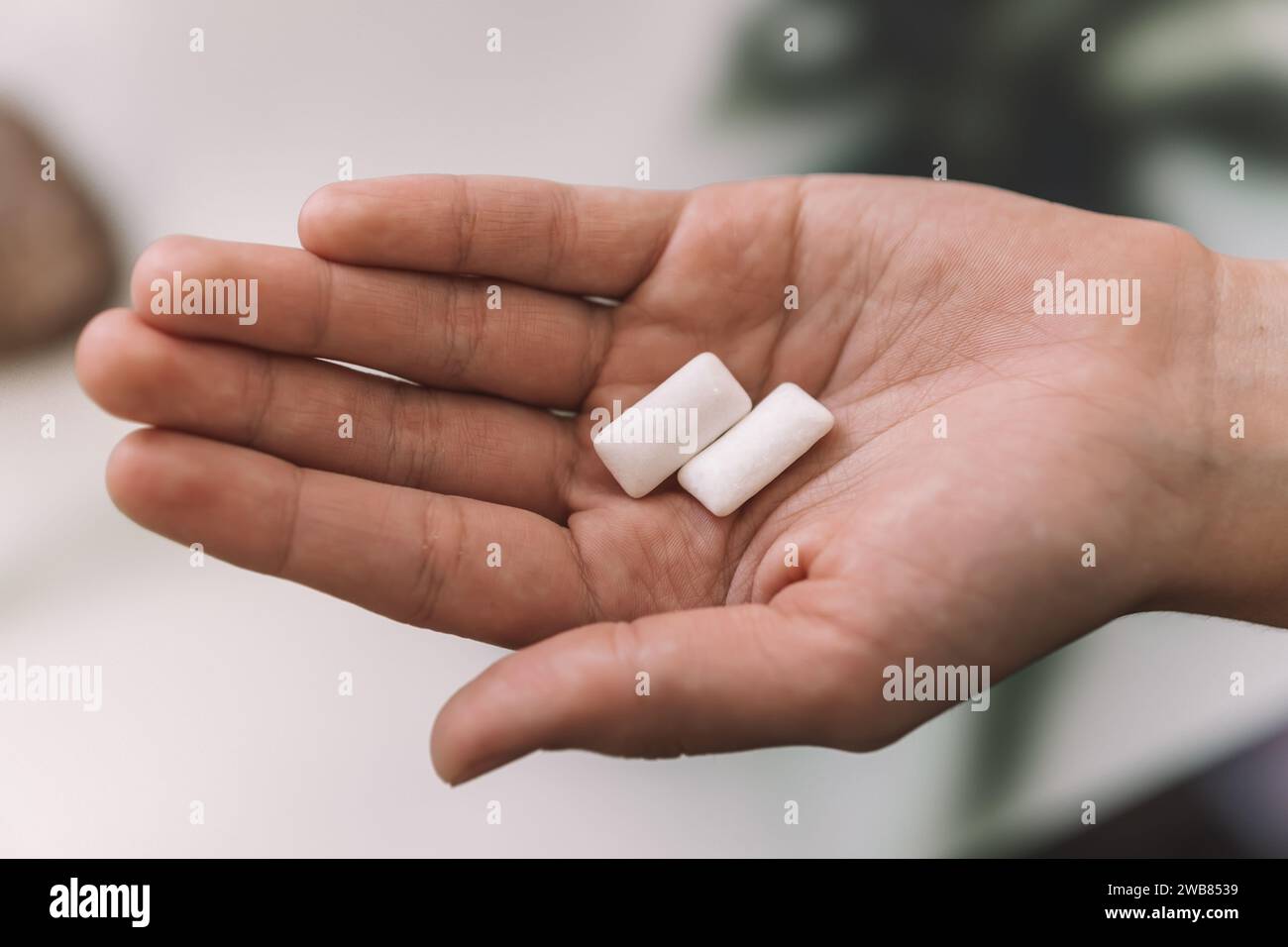 Young adult girl hand pouring white chewing gum pads from green pack in ...