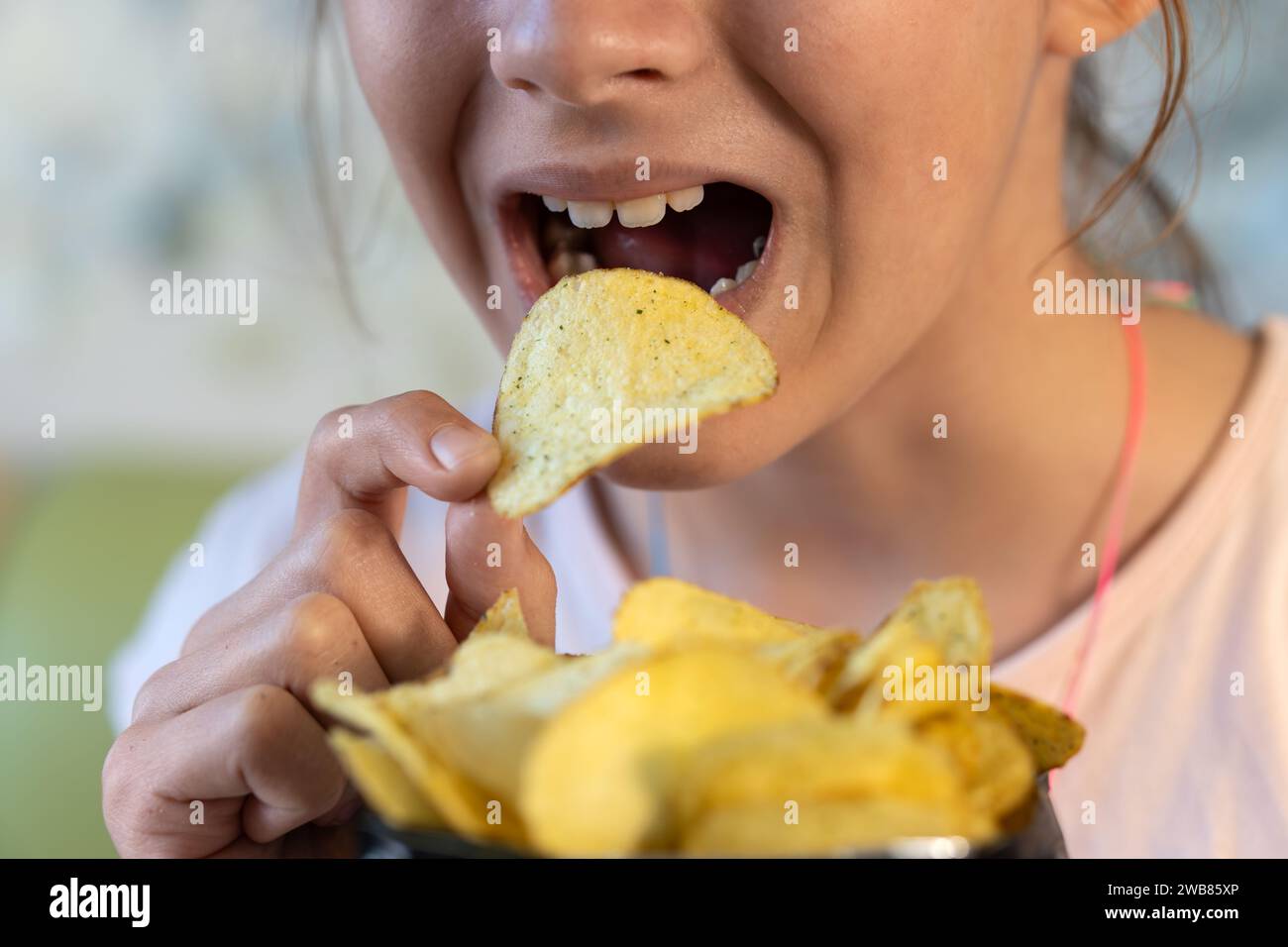 little caucasian girl eats chips with an appetite, opening her mouth ...