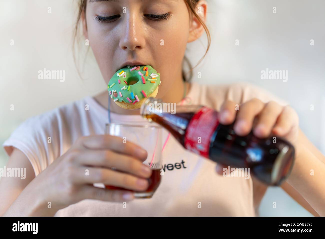 Little girl eating doughnut messily. A sweet cupcake in hand. The girl ...