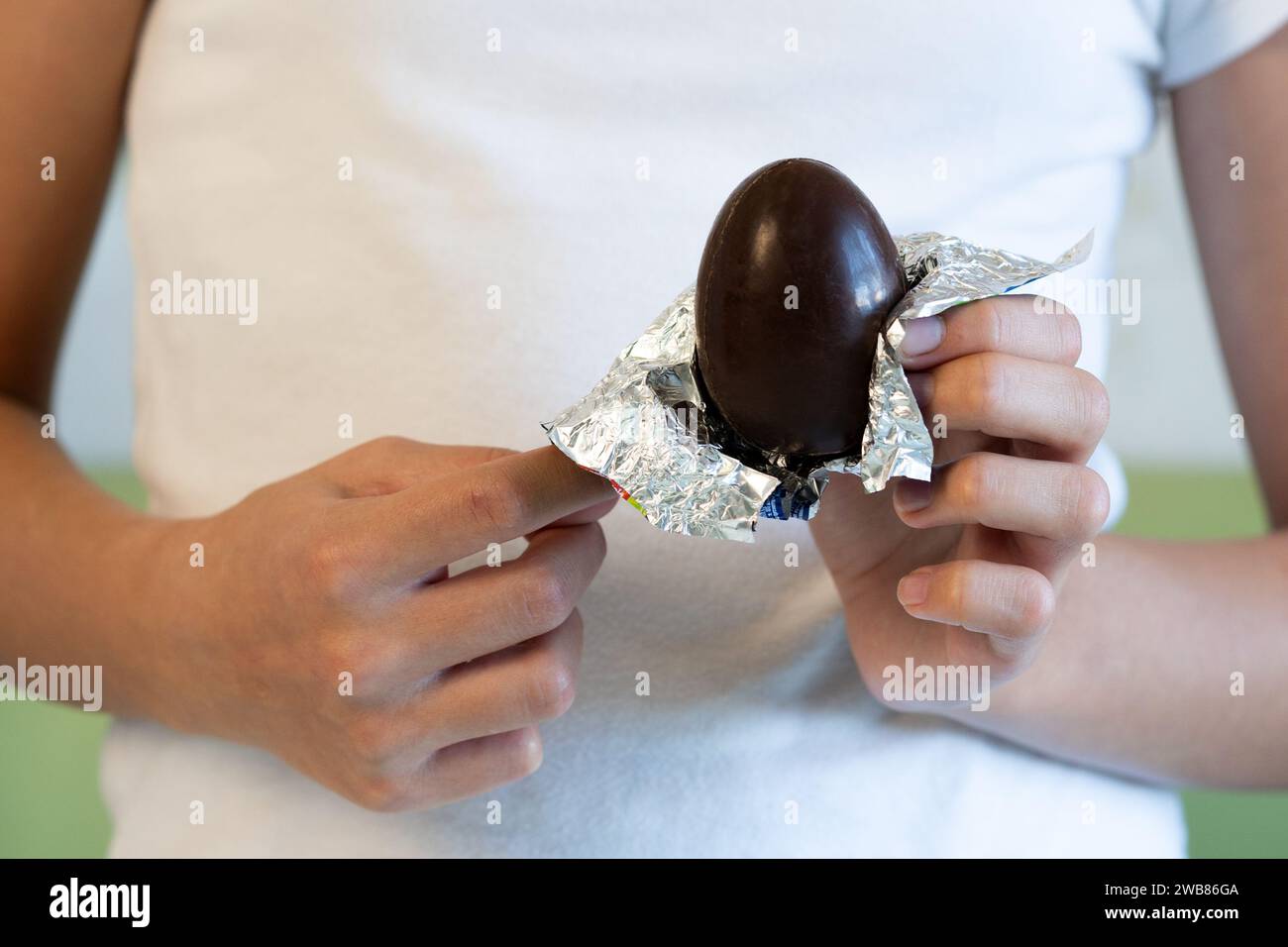 A child opens a chocolate egg. chocolate egg in the hands of a teenage ...