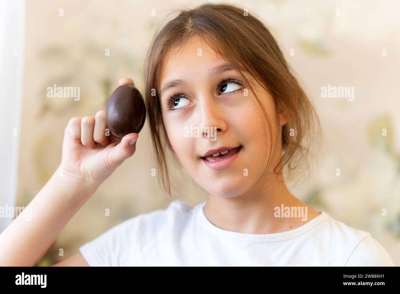 A child opens a chocolate egg. The girl is surprised by the surprise ...