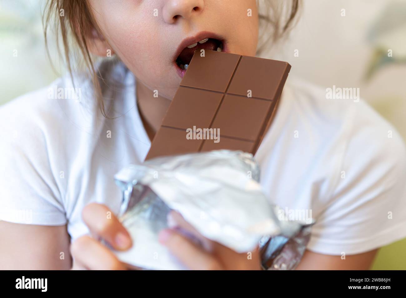 child girl with long hair biting chocolate Stock Photo - Alamy