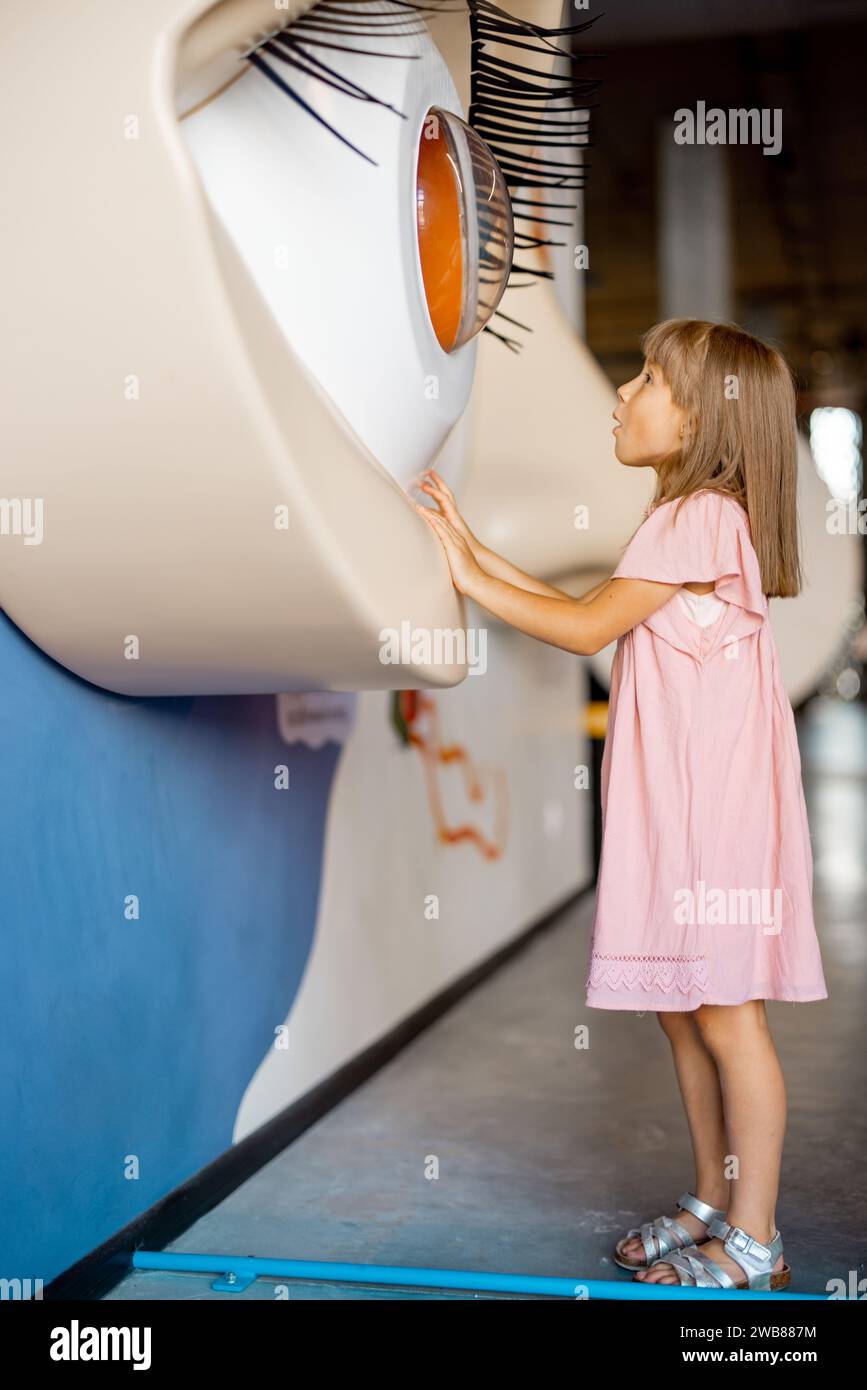 Little girl looks on a big eye model Stock Photo - Alamy