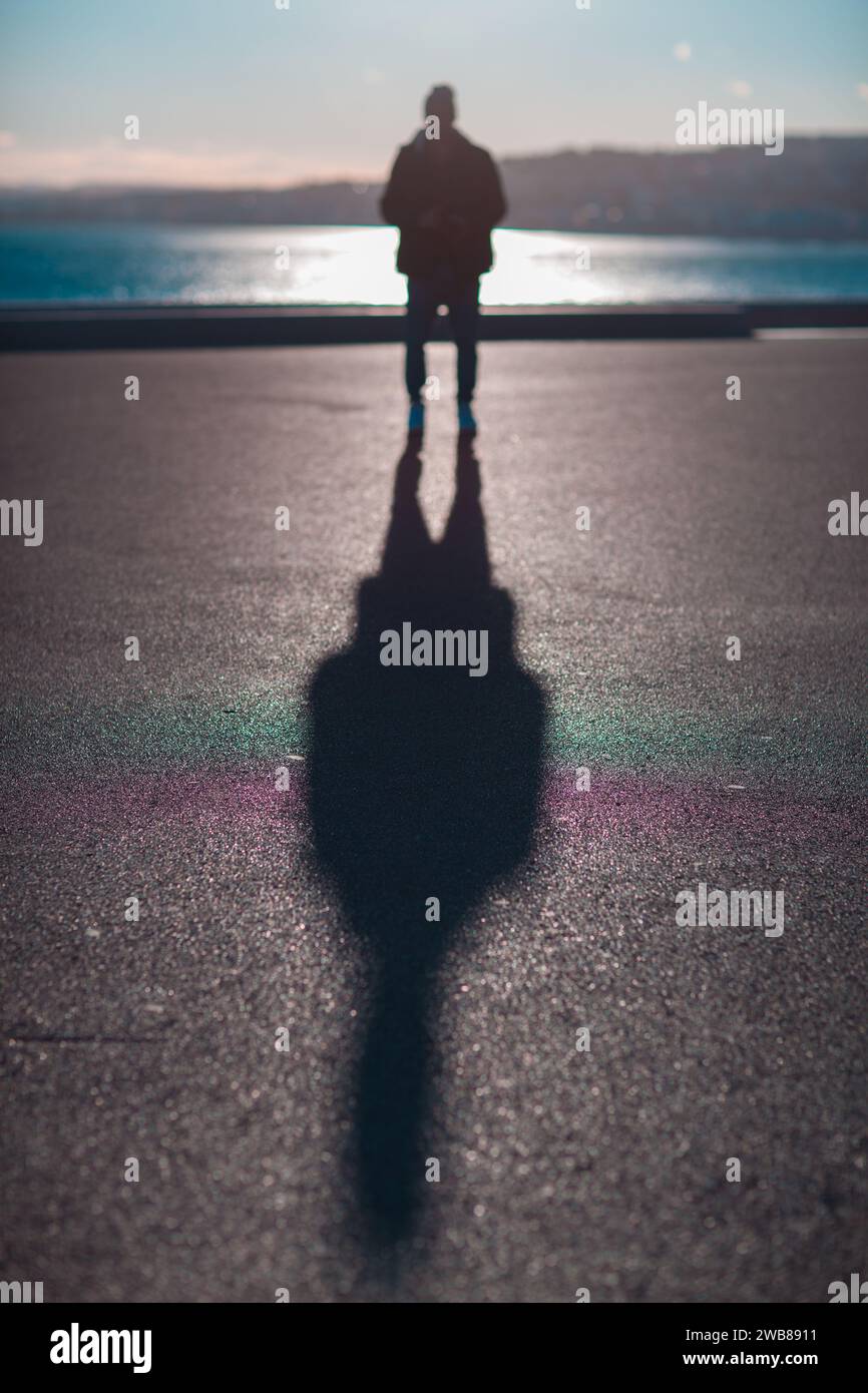 A silhouetted person standing against the backdrop of a bright sunlit ...