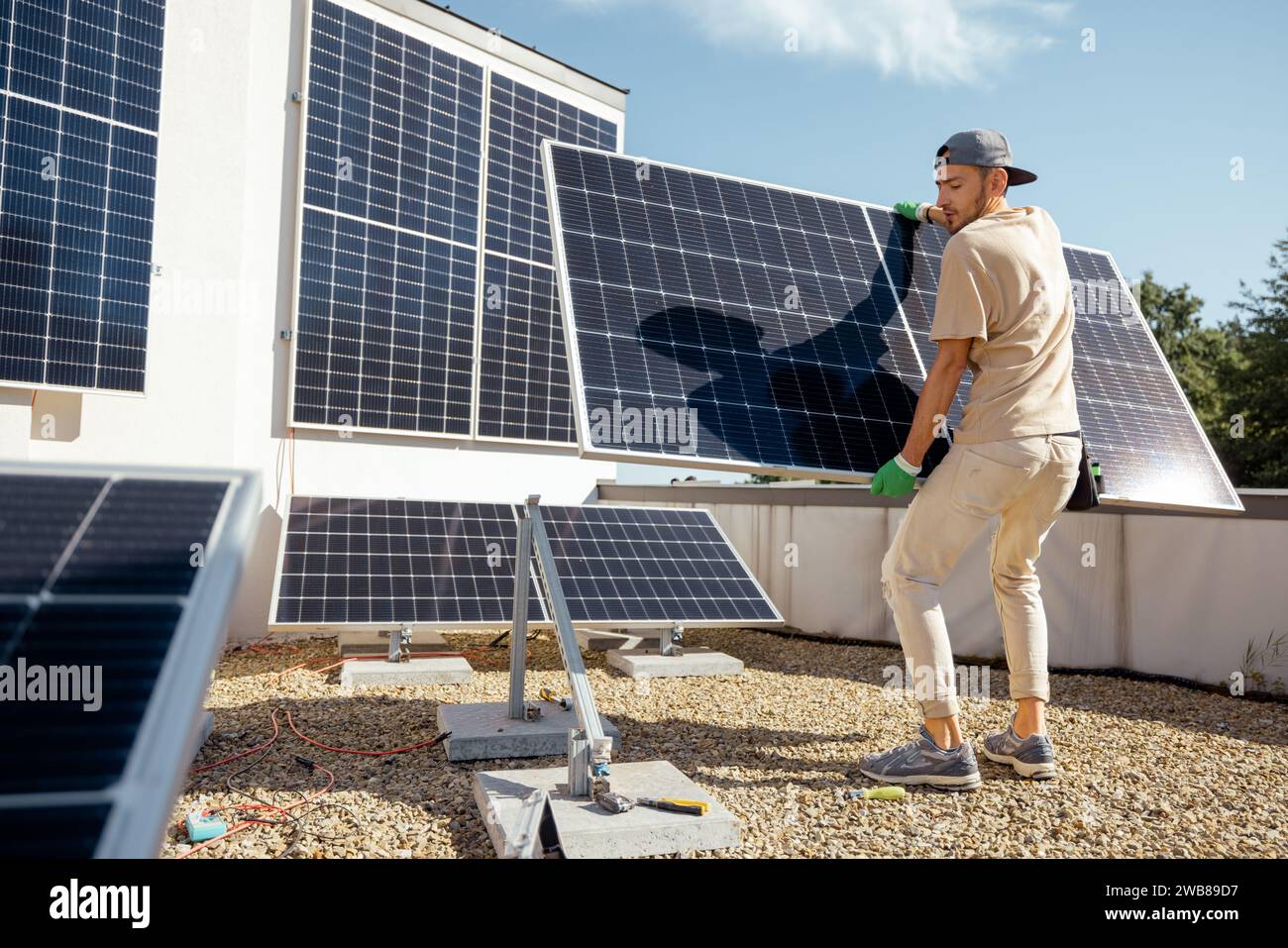 Man installing solar panels on a rooftop Stock Photo - Alamy