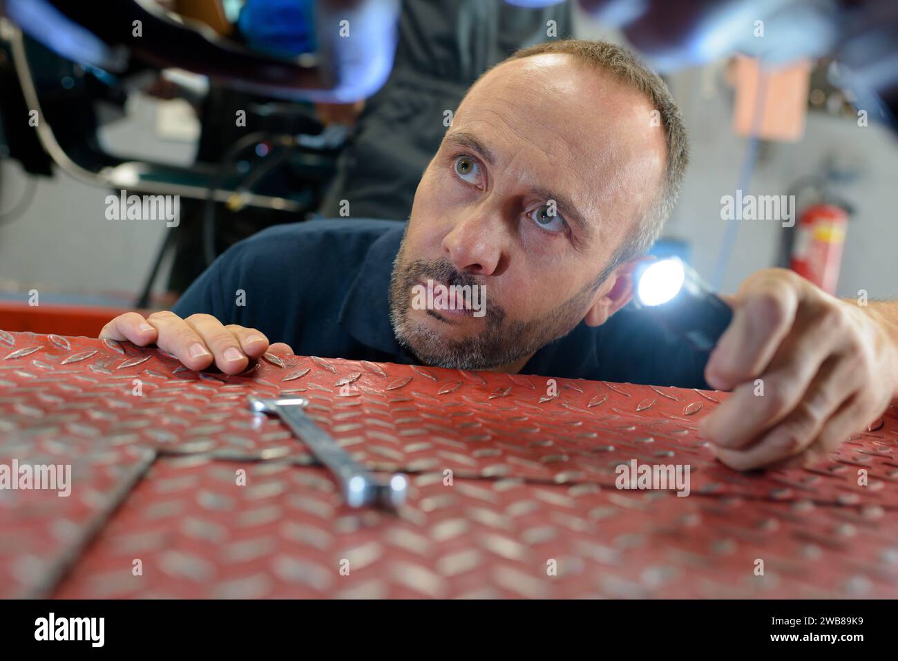 mechanic inspecting vehicle raised on chequerplate ramps Stock Photo ...