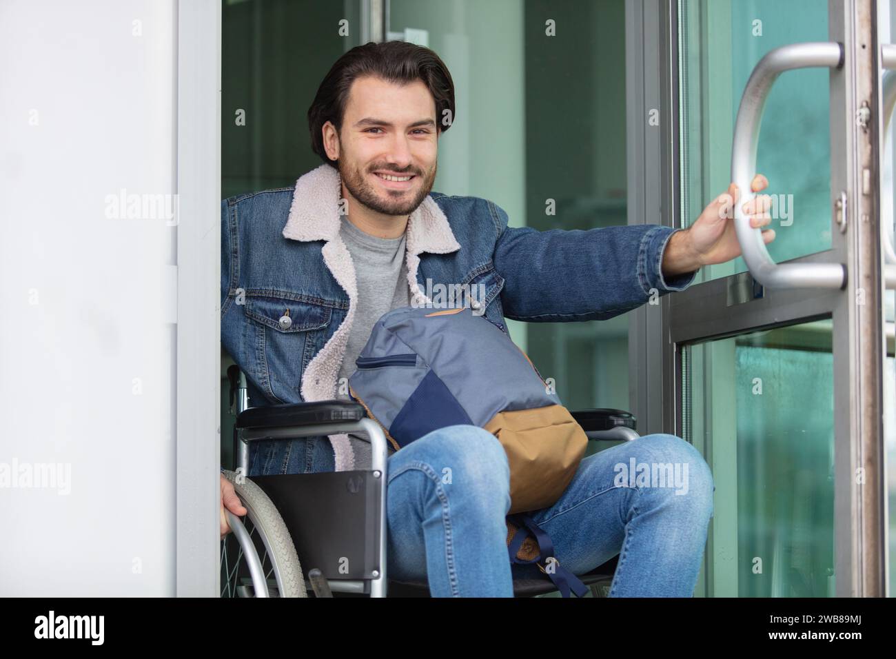a disabled man on wheelchair exiting a building Stock Photo - Alamy