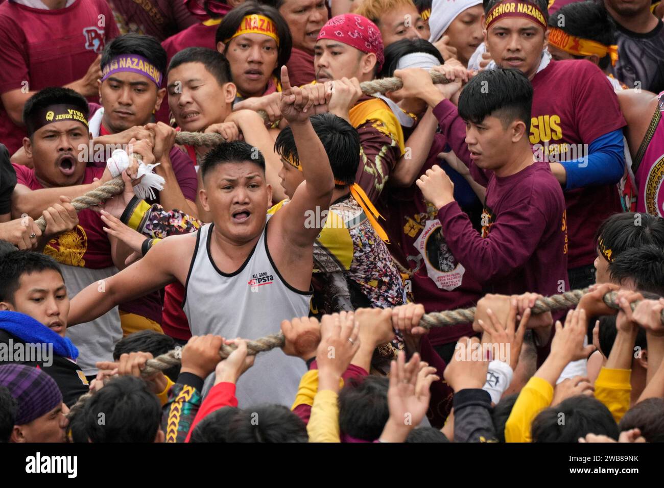 Devotees grab the rope as they pull the glass-covered cart carrying ...