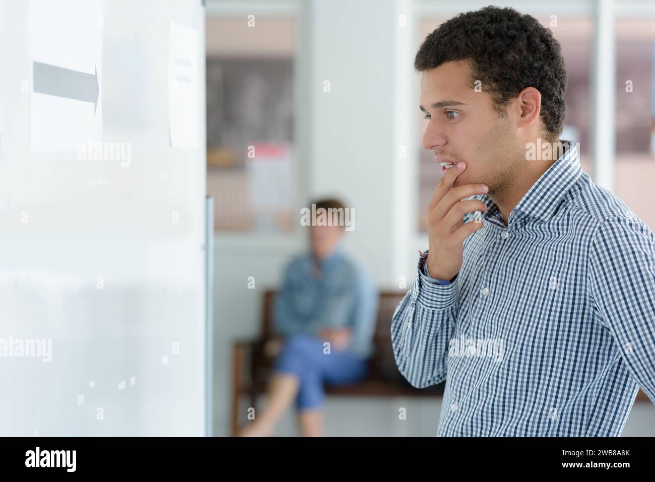 confused young man looking at notice board Stock Photo - Alamy