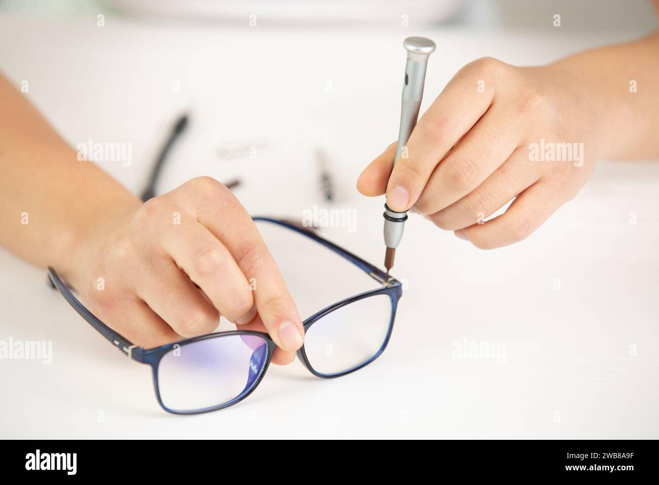optician repairing spectacles with tool in optical store Stock Photo ...