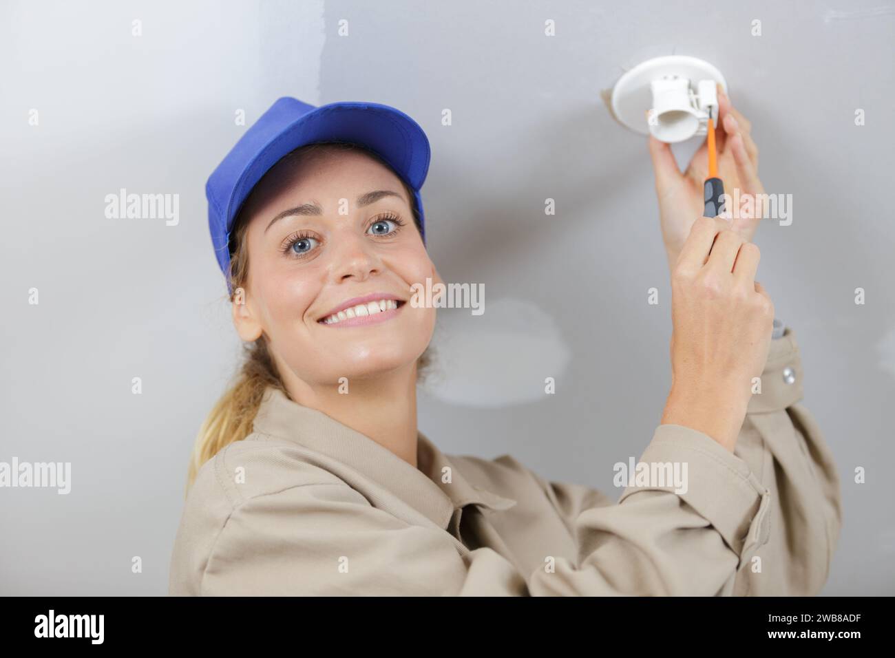 female electrician mounting light fitting Stock Photo - Alamy