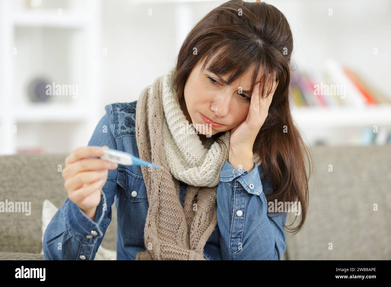 sick young woman checking body temperature with thermometer Stock Photo ...