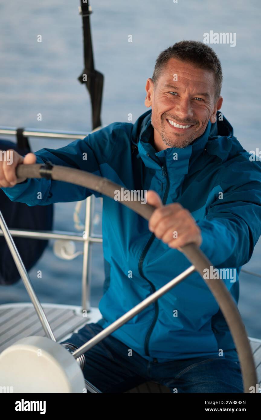 Good-looking mature man sailing a yacht and looking confident Stock ...