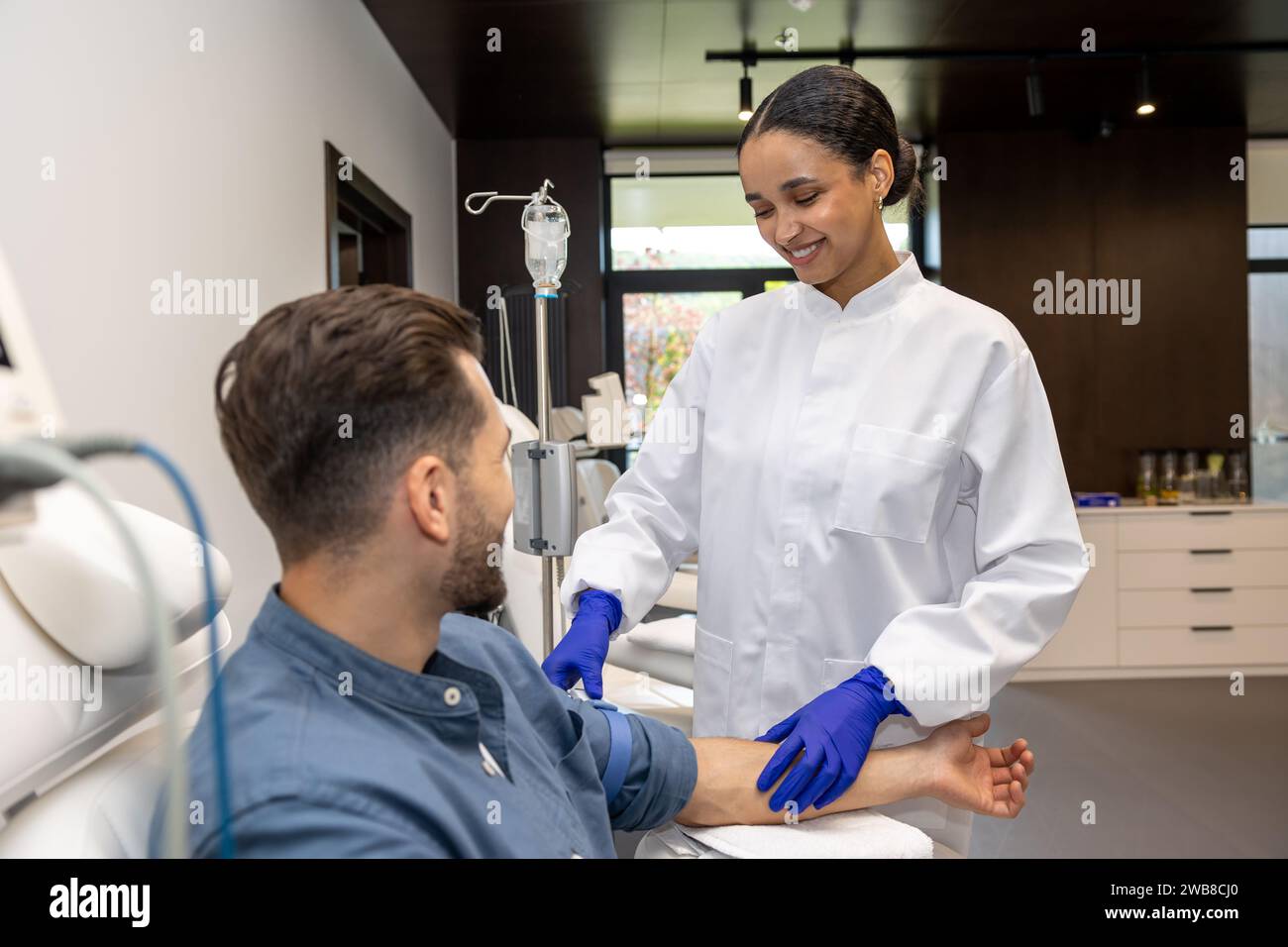 Doctor cosmetologist preparing male client arm for insertion of drip ...