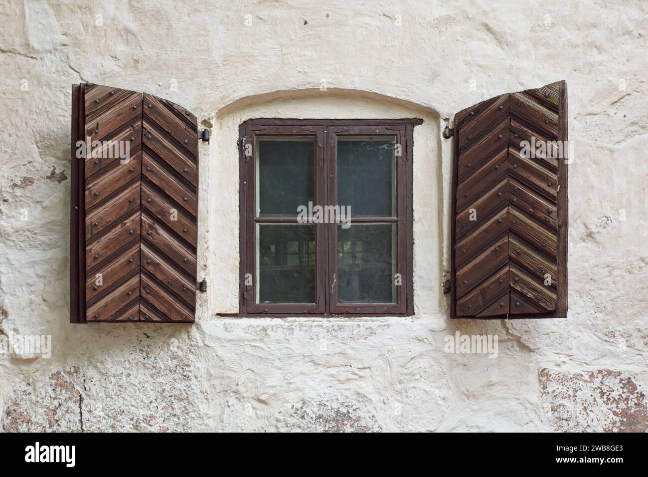 Brown painted wood frames window with brown wood covers on a stone ...