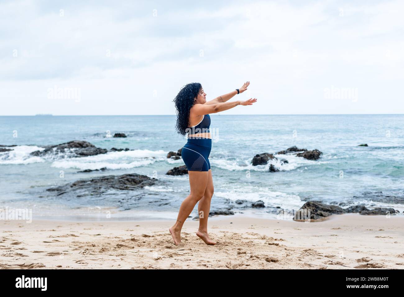 Fitness woman, athlete, doing jumping jacks on the beach sand. Healthy ...