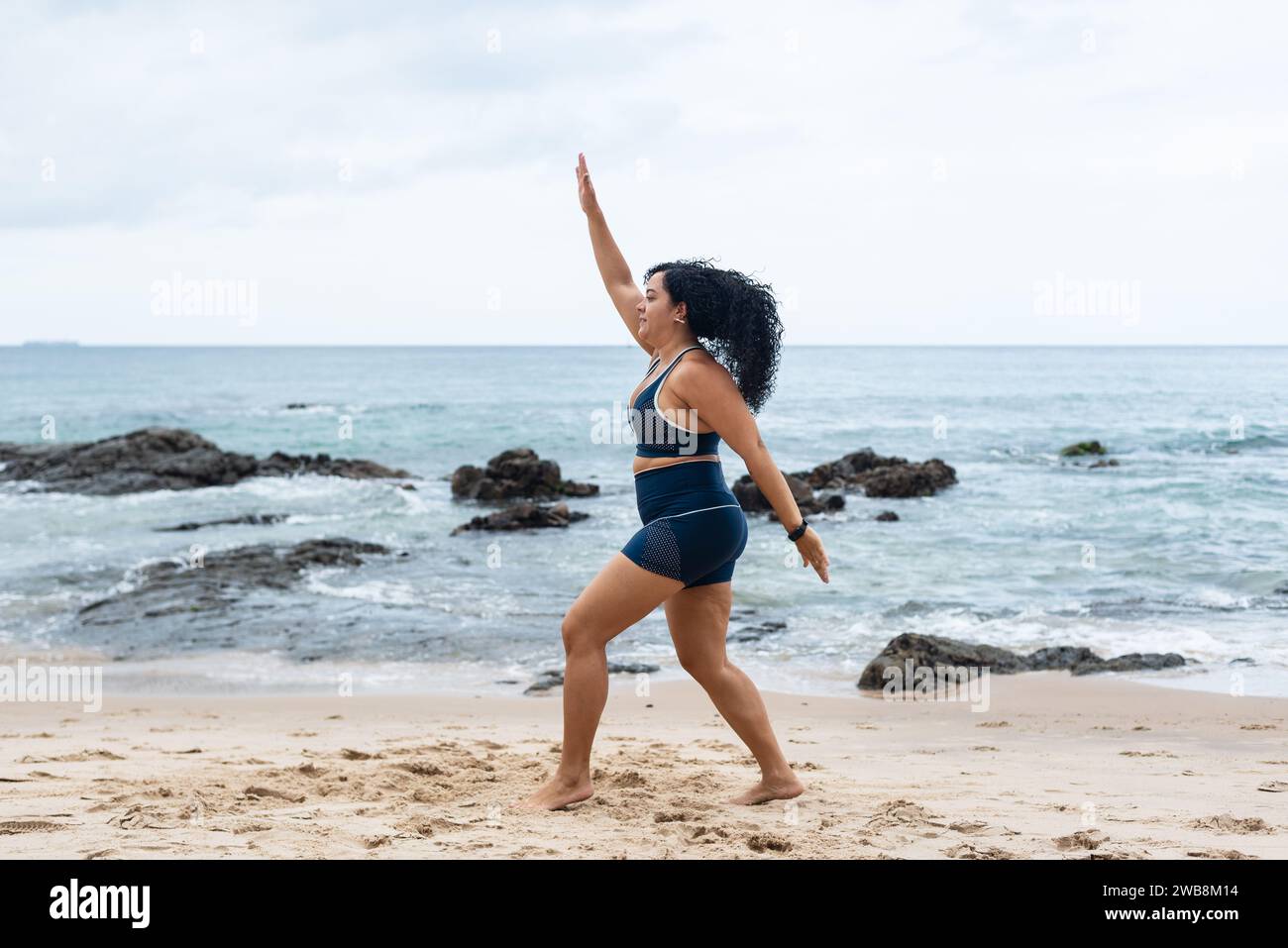 Fitness woman, athlete, doing jumping jacks on the beach sand. Healthy ...