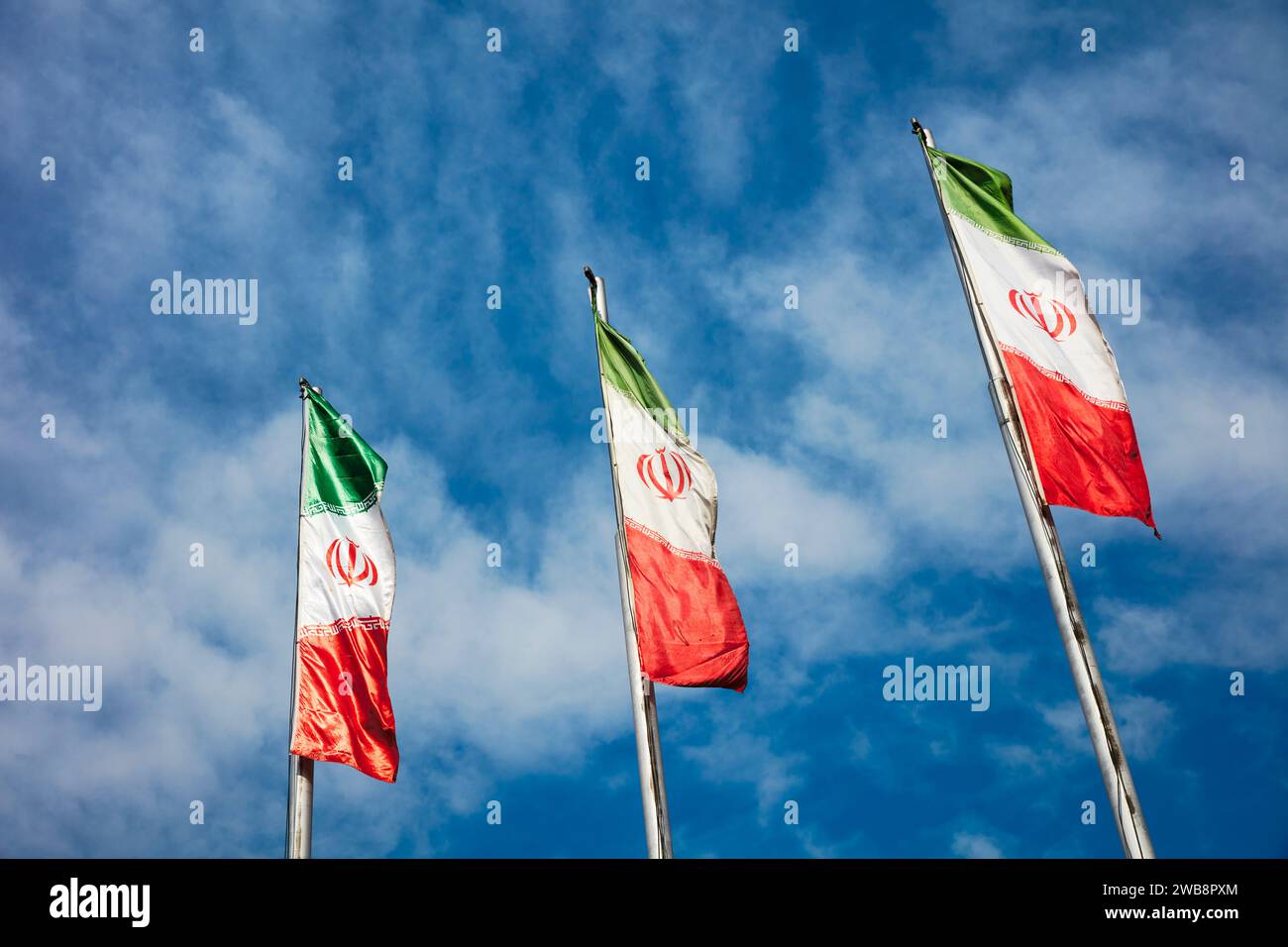 Iranian national flags waving in the wind against blue sky and white ...