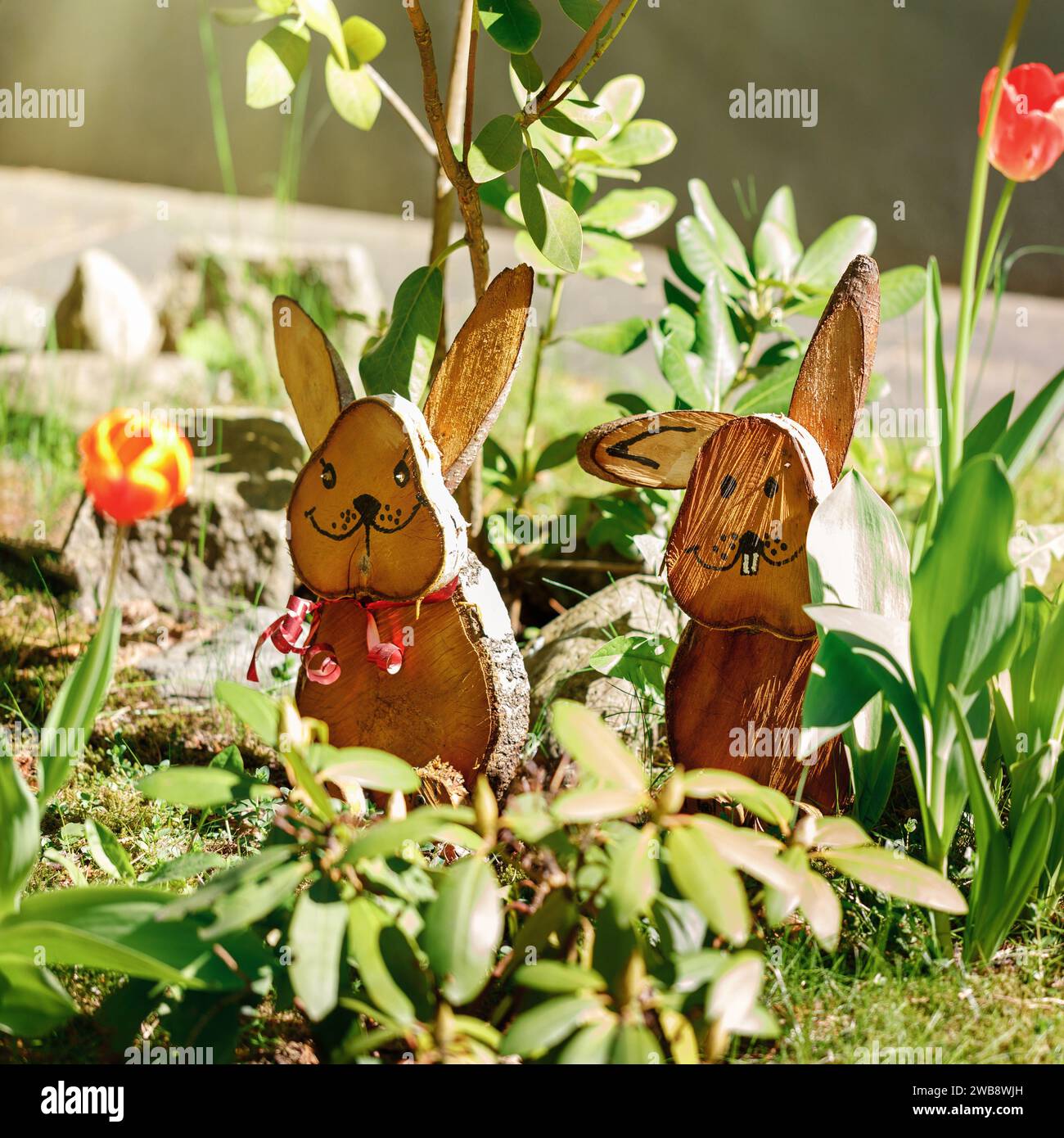 Handmade two wooden easter rabbit, decor stands in flower garden ...