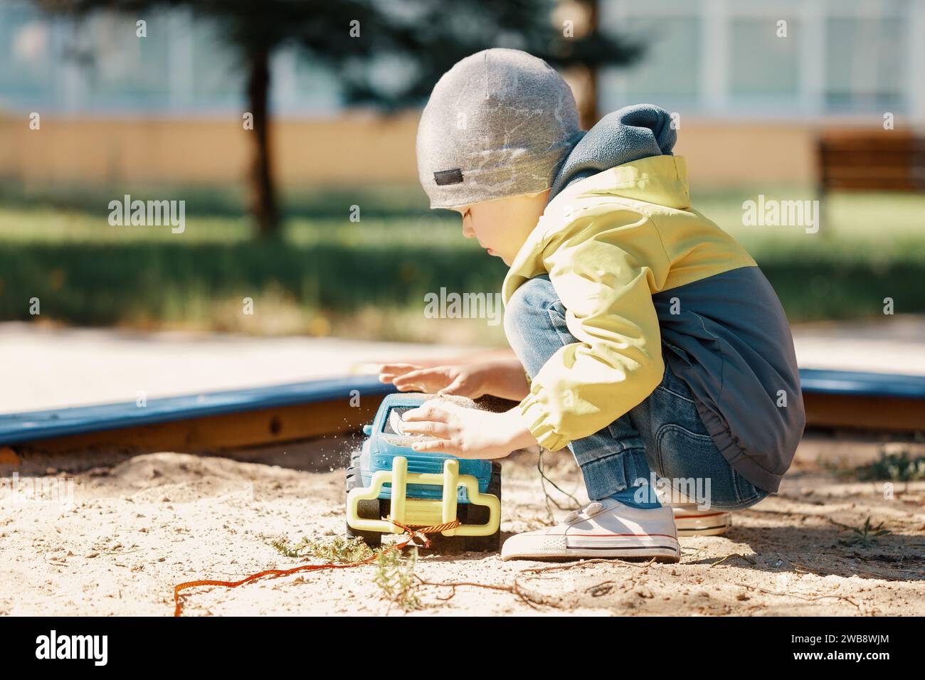 A little boy playing in the sandbox at the playground outdoors. Toddler ...