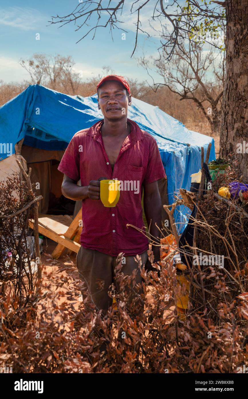 african man standing in front of a shack in a refugee camp, homeless ...