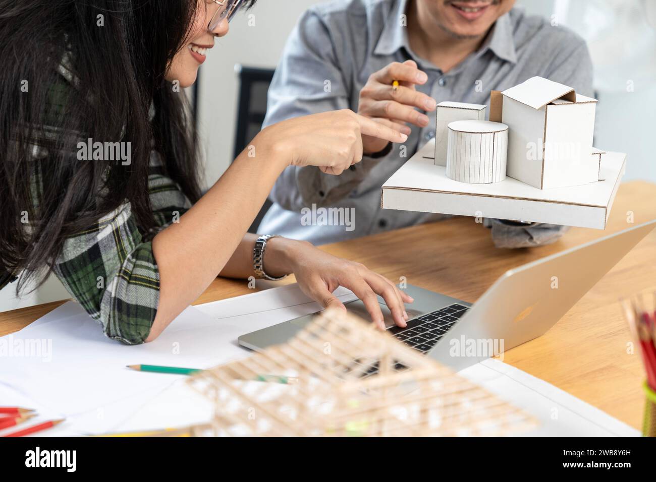 A group of young architects working with a model of a house in the ...
