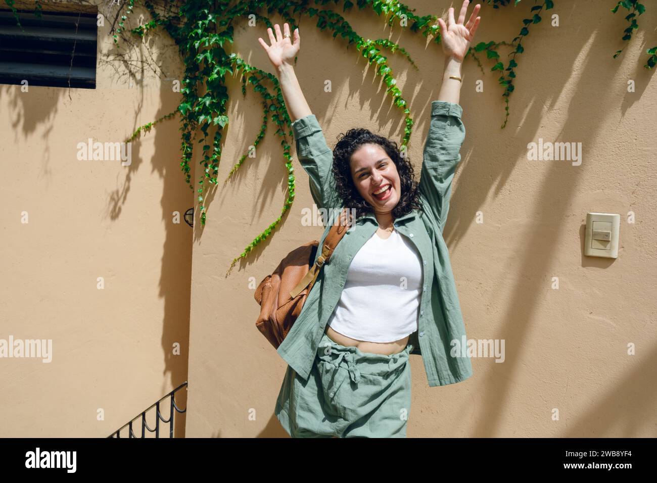 young Latin Venezuelan woman with curlers and green clothes, happy on ...