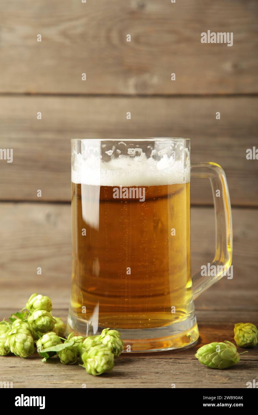 Glass of fresh beer with green hops on a grey background. Top view ...