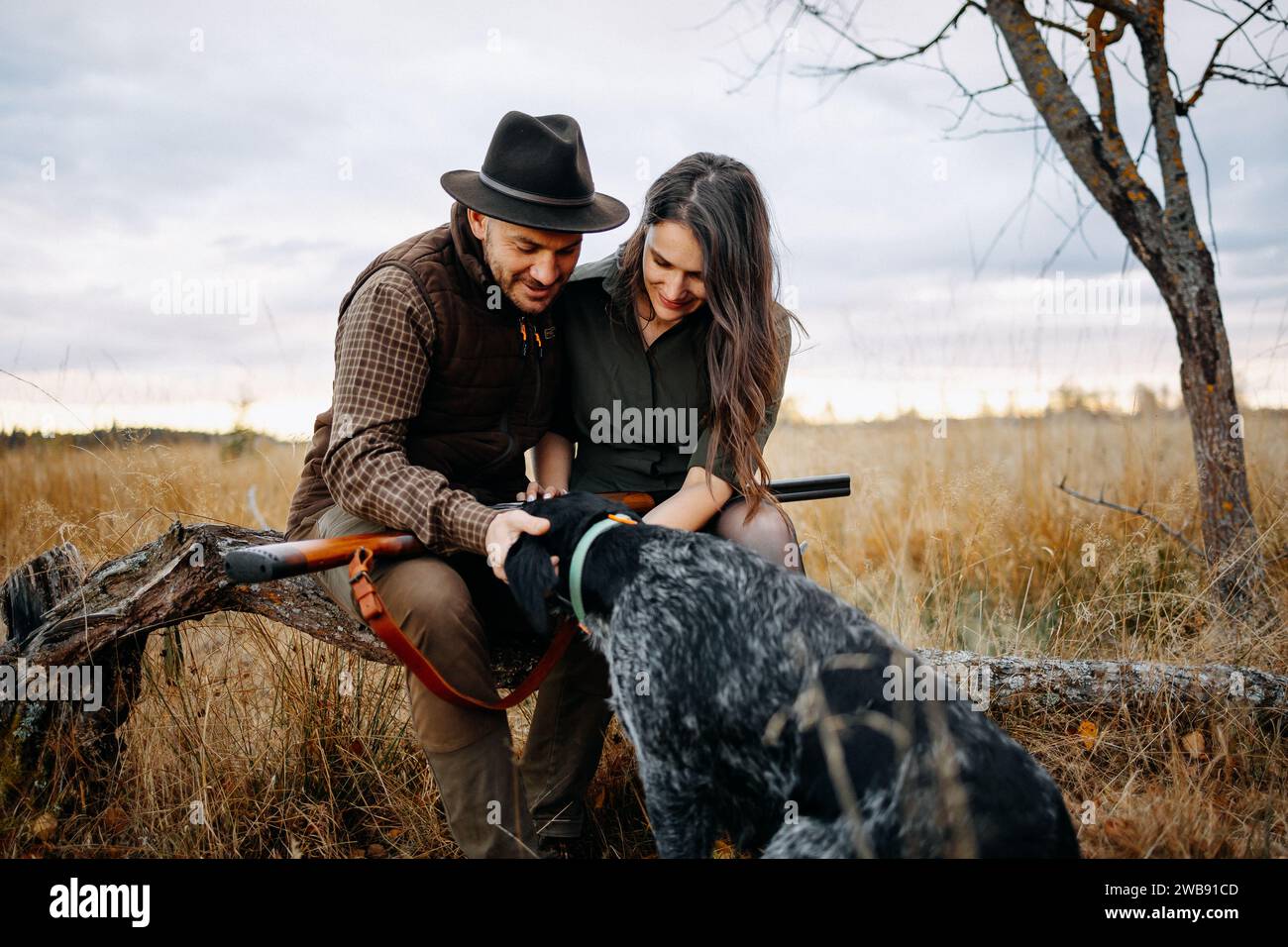 Young lovely couple, the hunter and his lady petting their dog out in ...