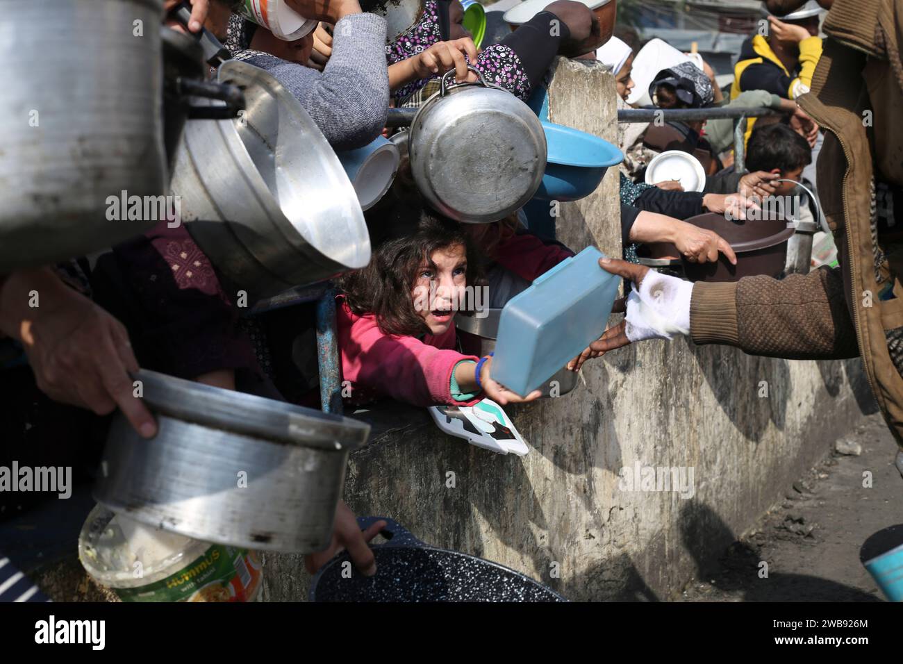 Palestinians line up for free food during the ongoing Israeli air and ...