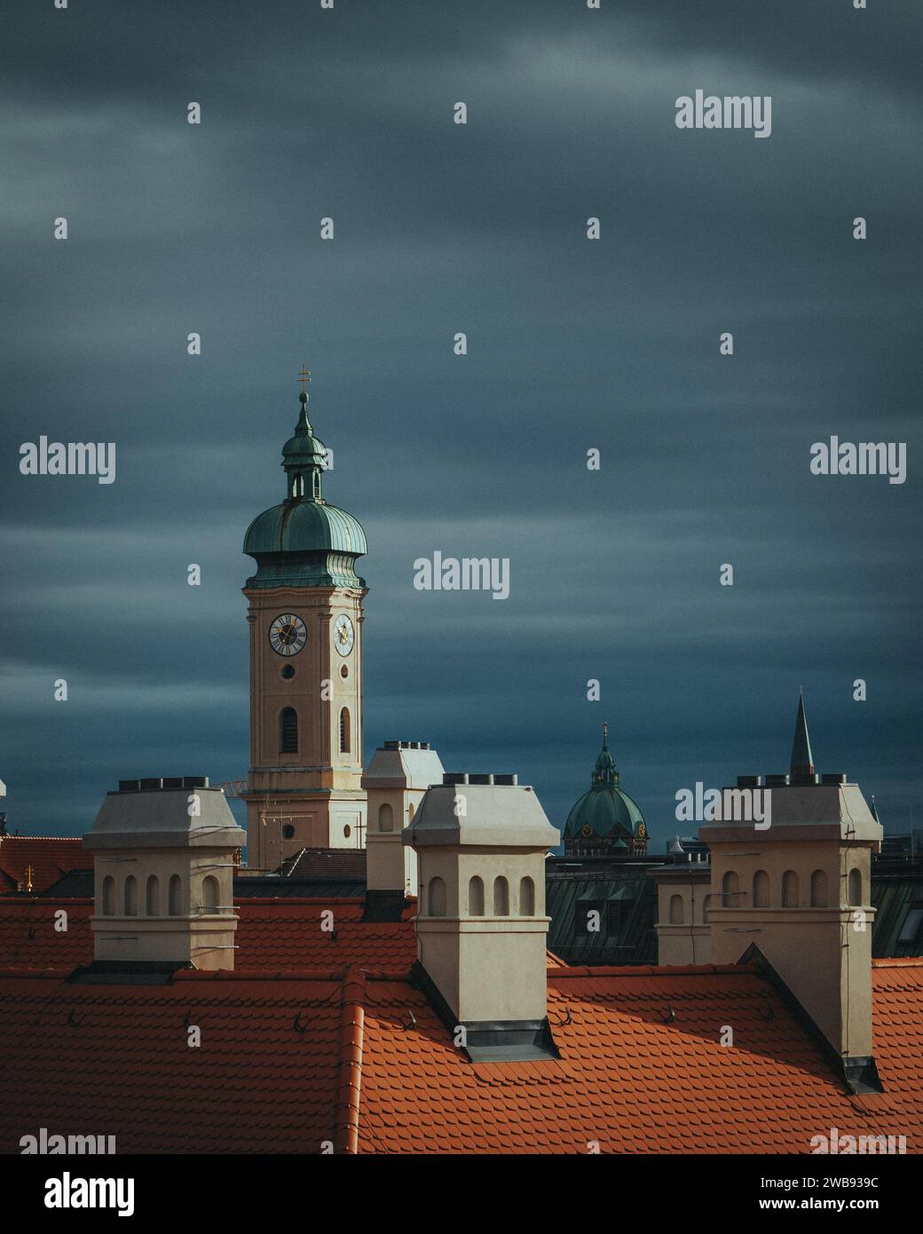 A majestic clock tower rising above a terracotta-tiled roof in Munich ...
