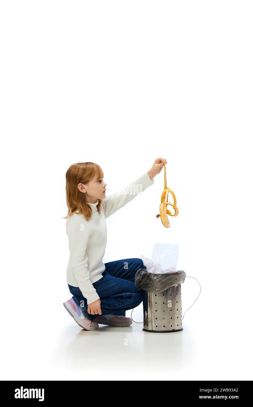Little girl, child taking away garbage, throwing banana peel into trash ...