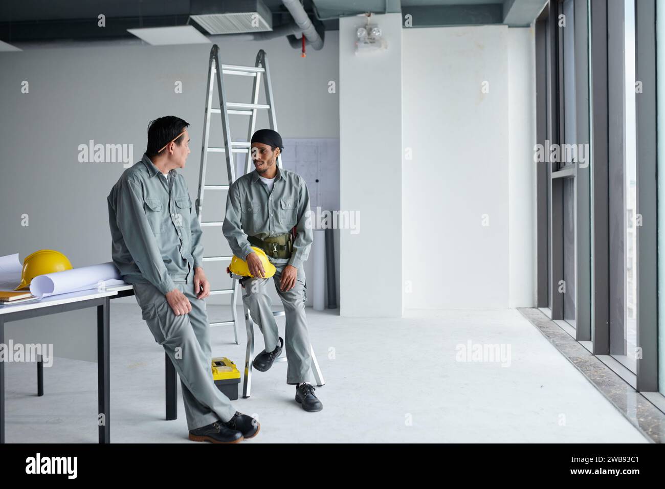Builders in grey uniform talking after finishing work in building after ...