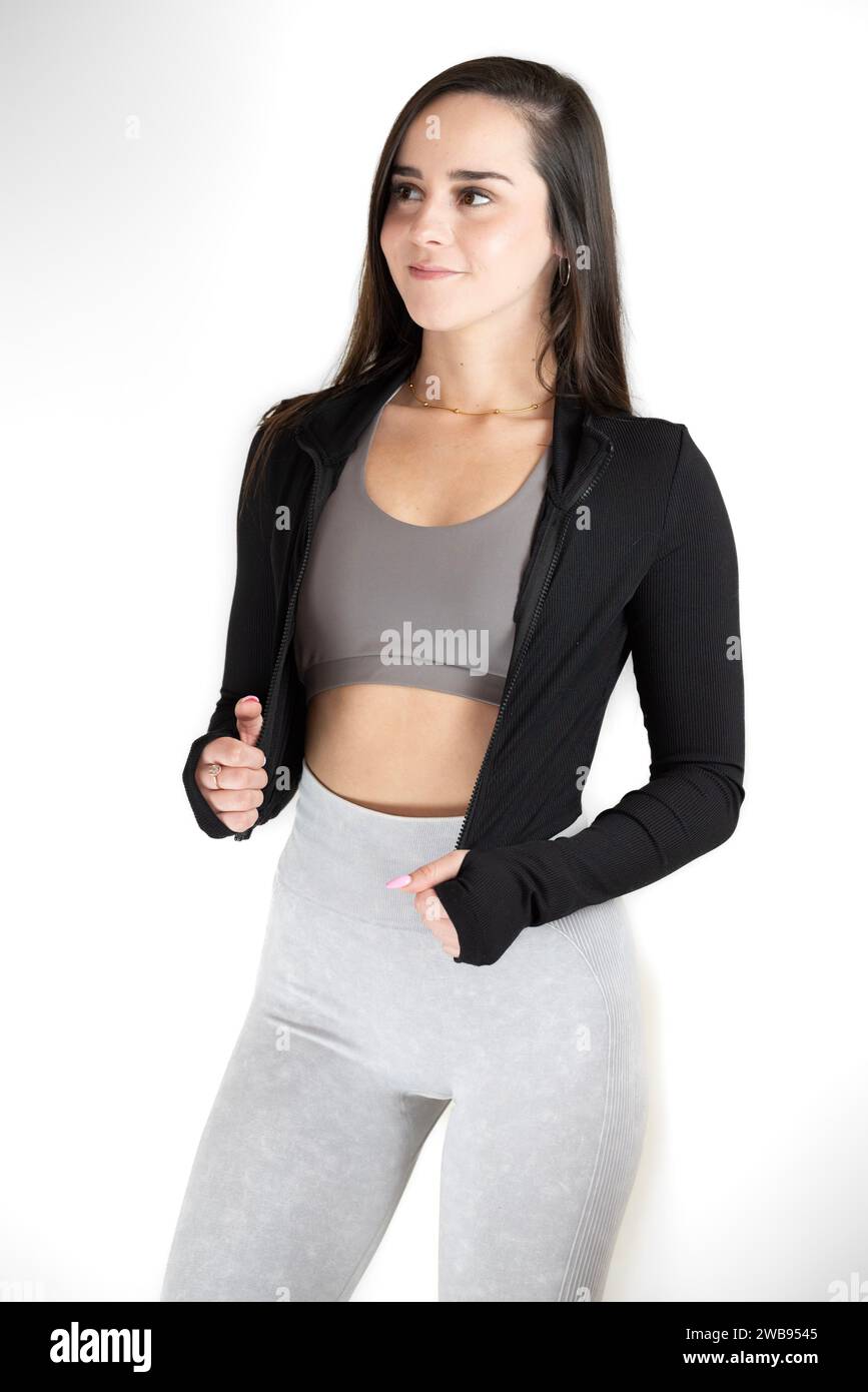 An attractive young woman wearing a black jacket and gray pants ...