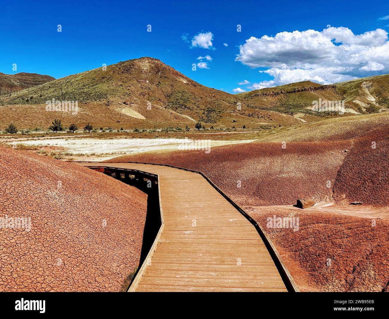 A wooden pathway cutting through the barren desert landscape, with a ...