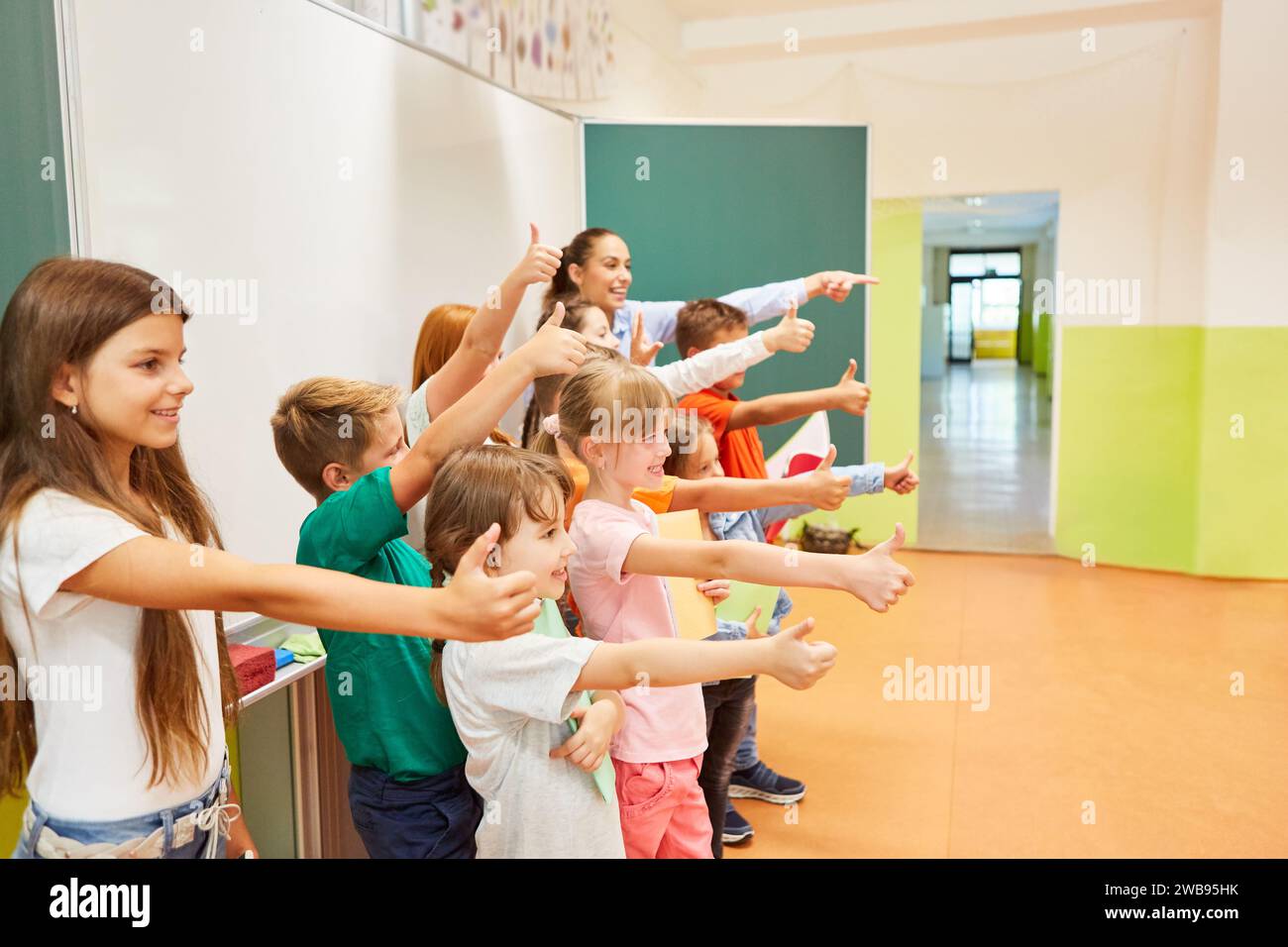 Group of cheerful students making thumbs up gesture while standing with ...