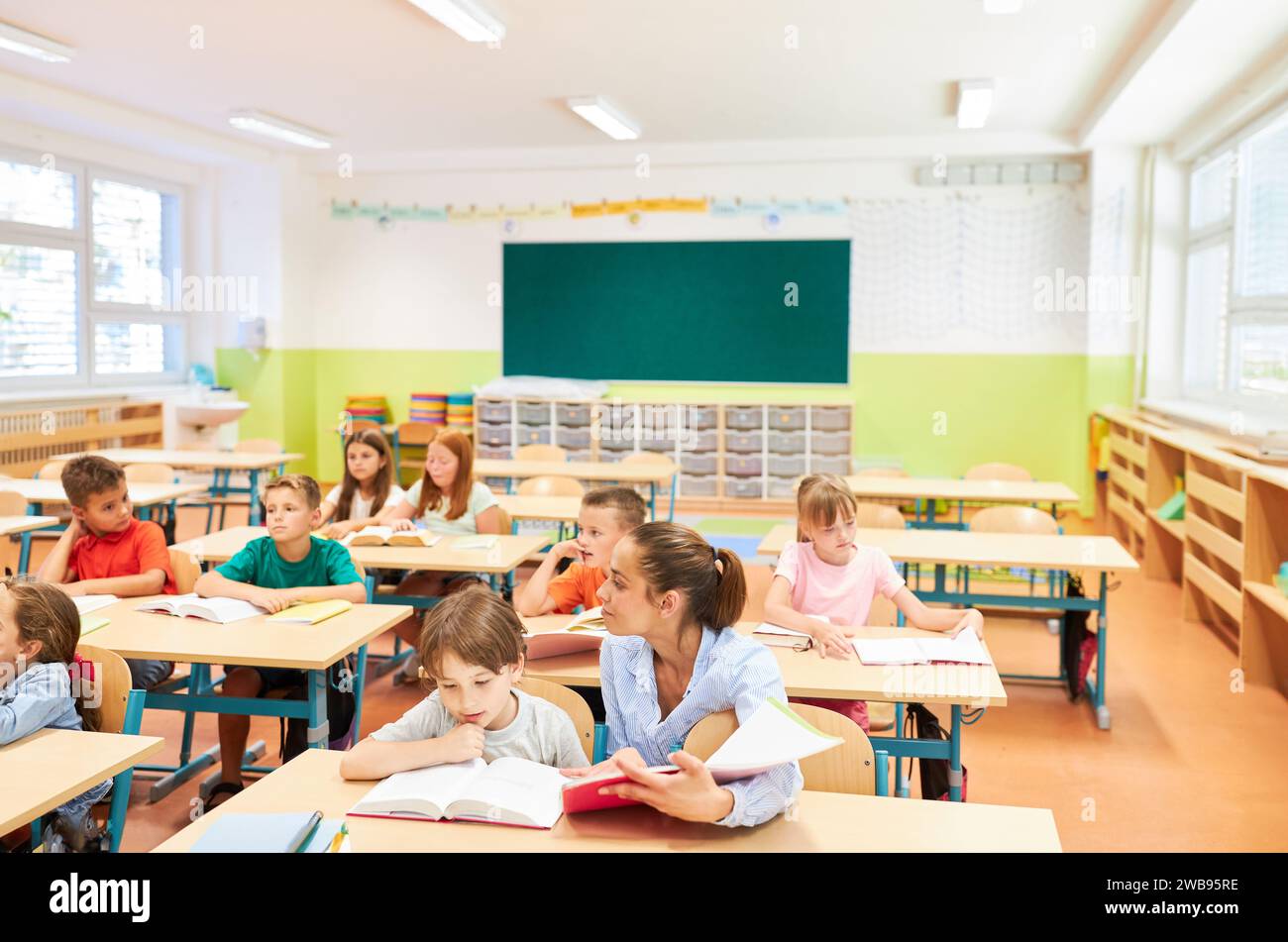Group of elementary school children studying together with teacher in classroom Stock Photo - Alamy