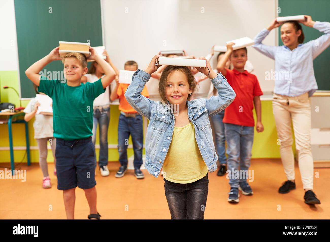 Elementary school students balancing books with teacher during activity ... Elementary school students balancing books with teacher during activity ...